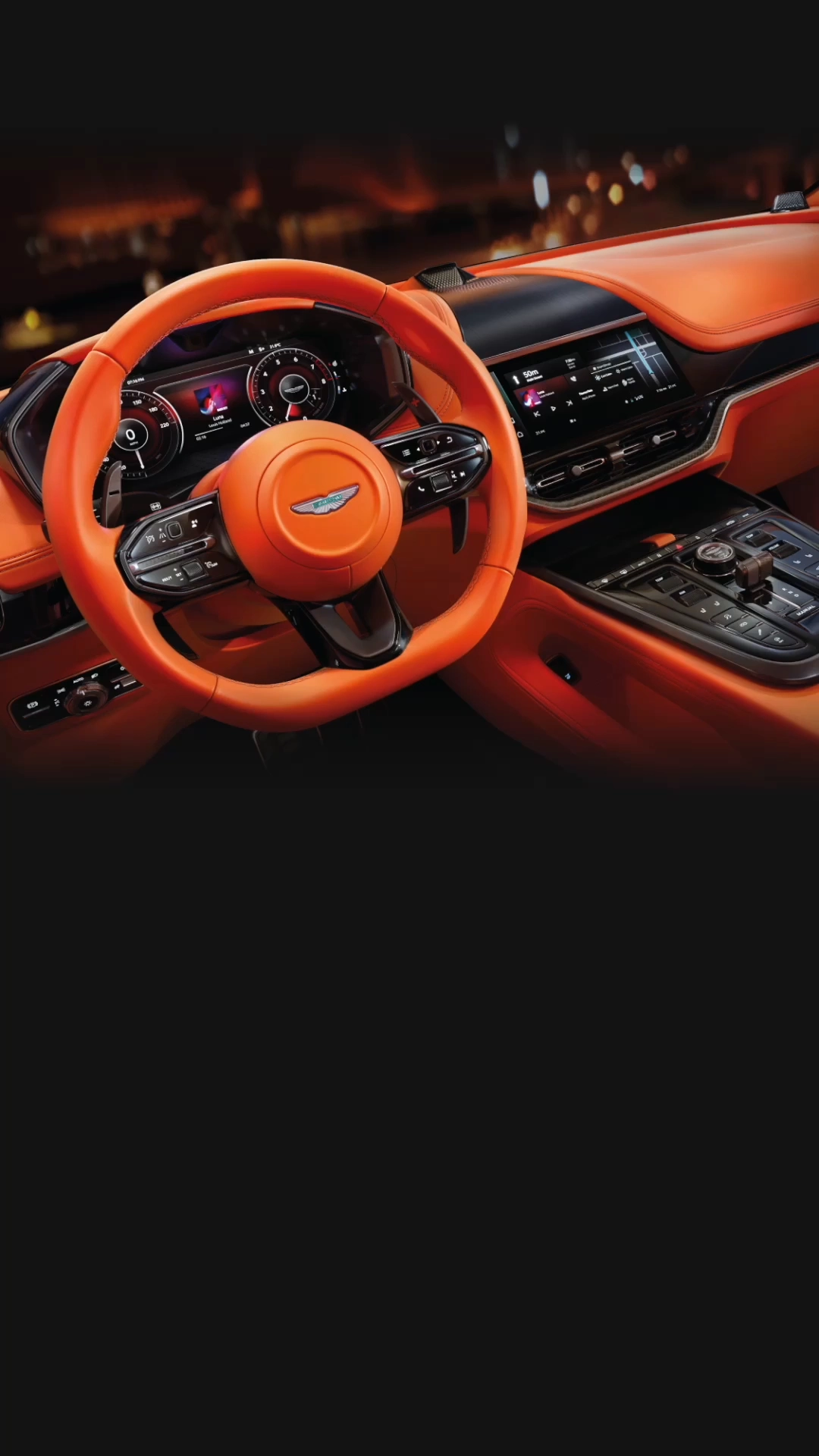 Interior view of driver's side in an orange Aston Martin DBX707