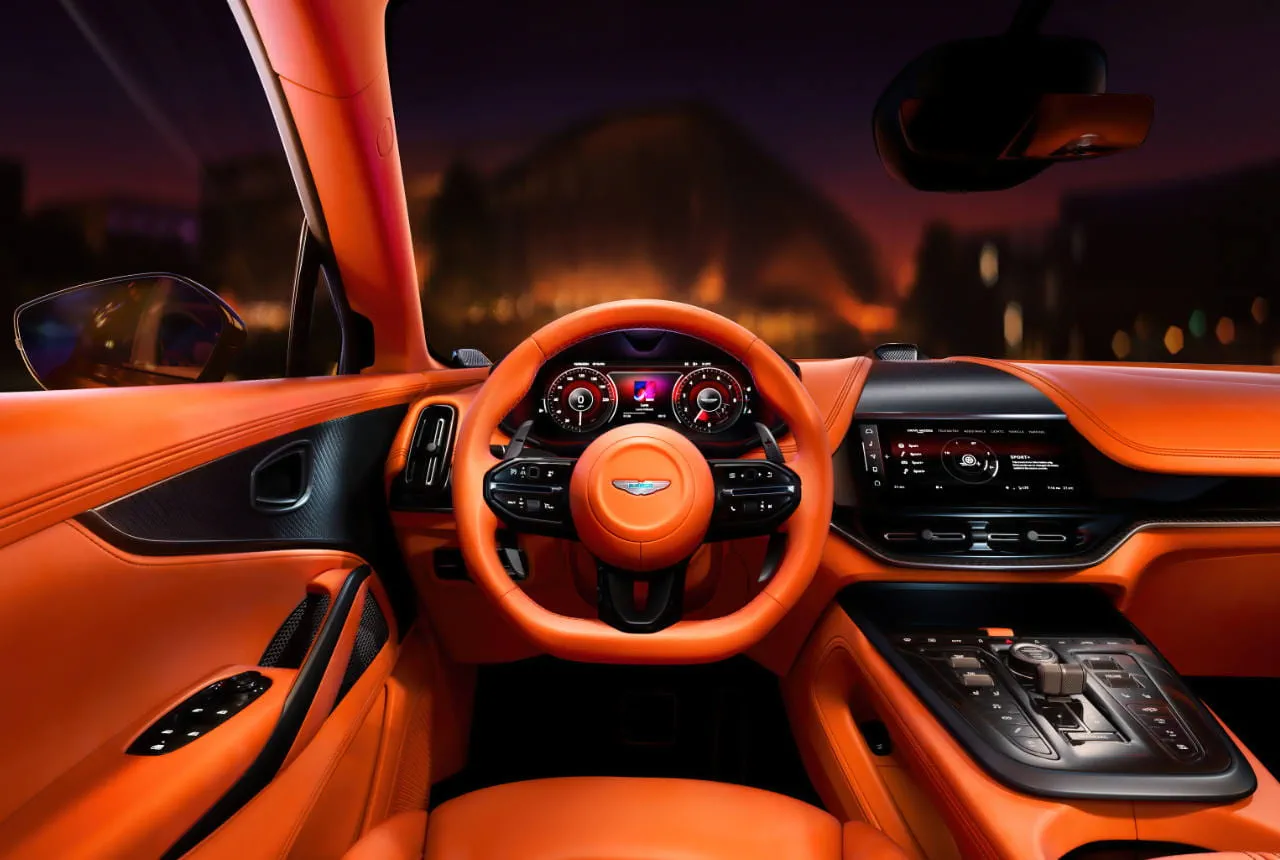 Interior view of driver's side in an orange Aston Martin DBX707